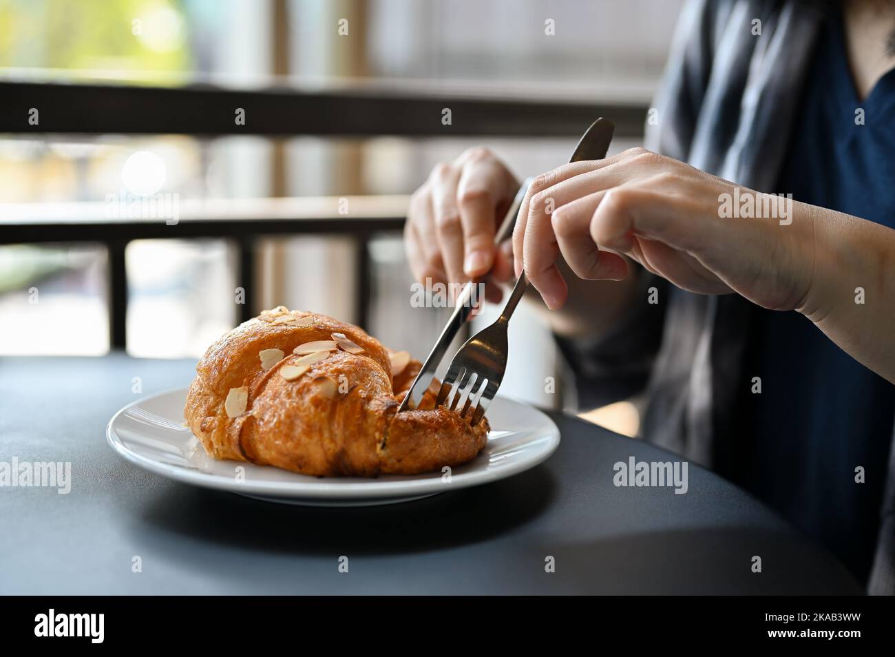 A female eating a delicious fresh French croissant with almond slice ...