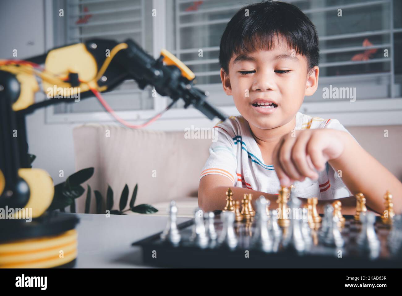 Asian little boy is playing chess with robot machine arm Stock Photo ...