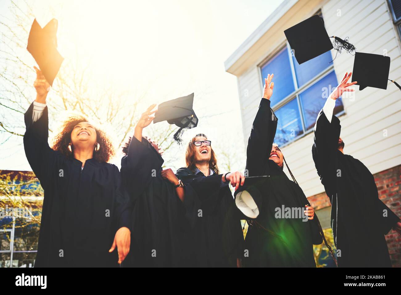 Celebrating our efforts. a group of students throwing their caps into the air after graduating ...