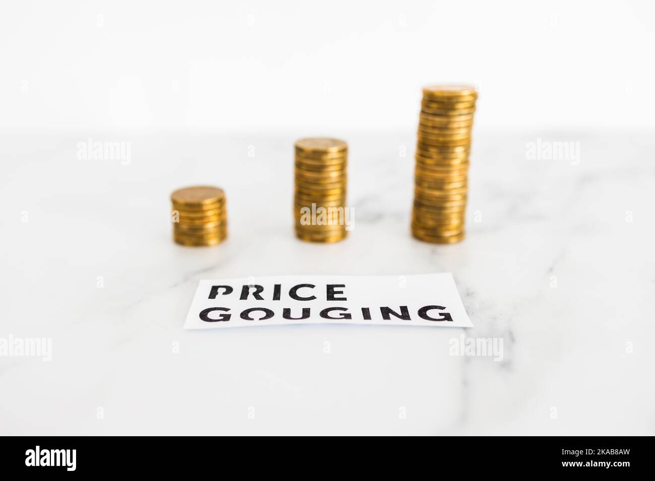 hand holding Price Gouging text in front of growing stacks of coins in ...