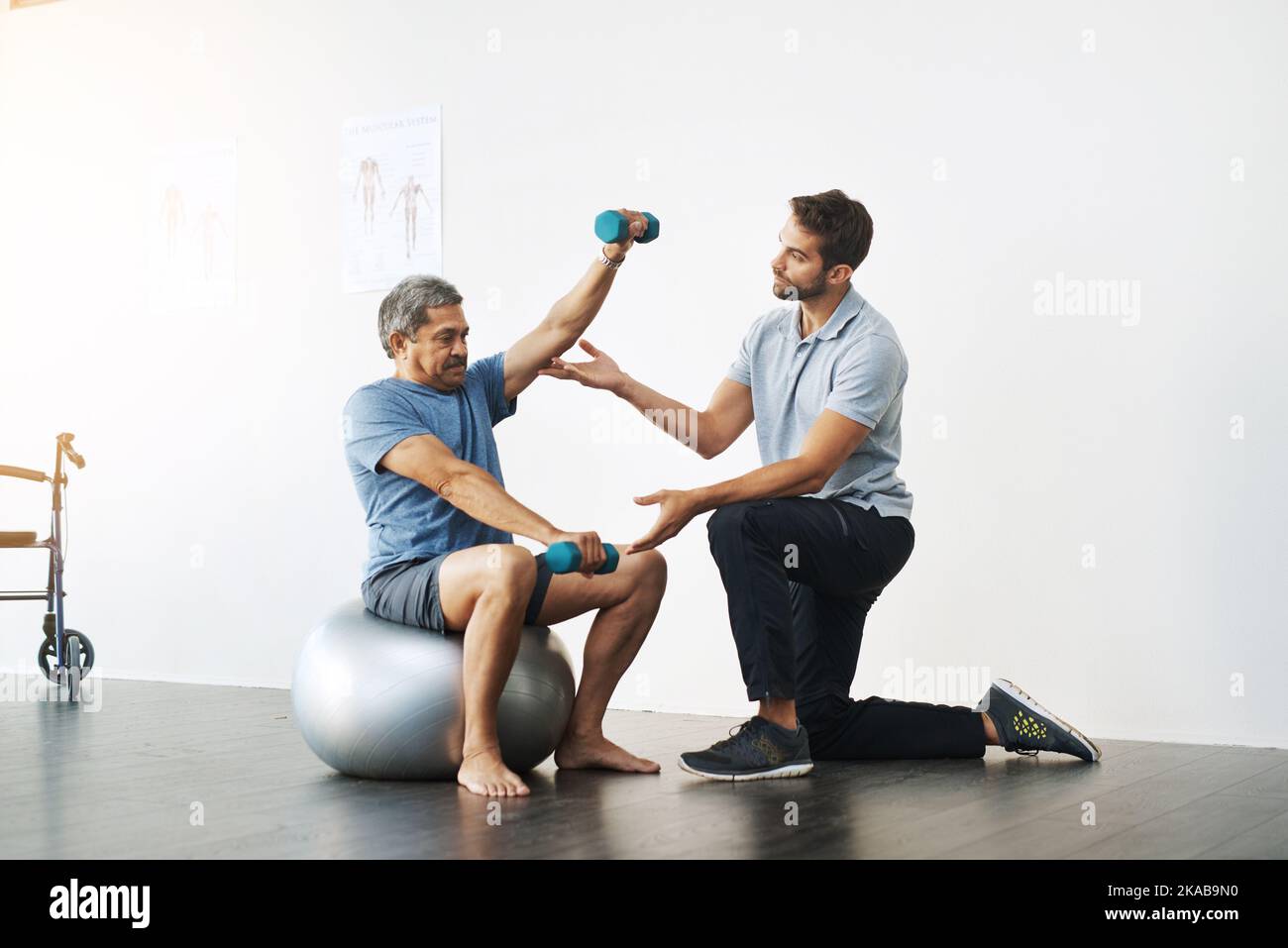 Slow and easy movements. a young male physiotherapist helping a mature ...