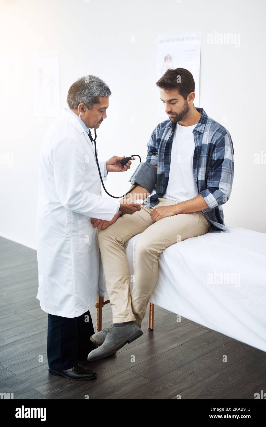 Deep breaths. a mature male doctor doing a check up on a young patient ...