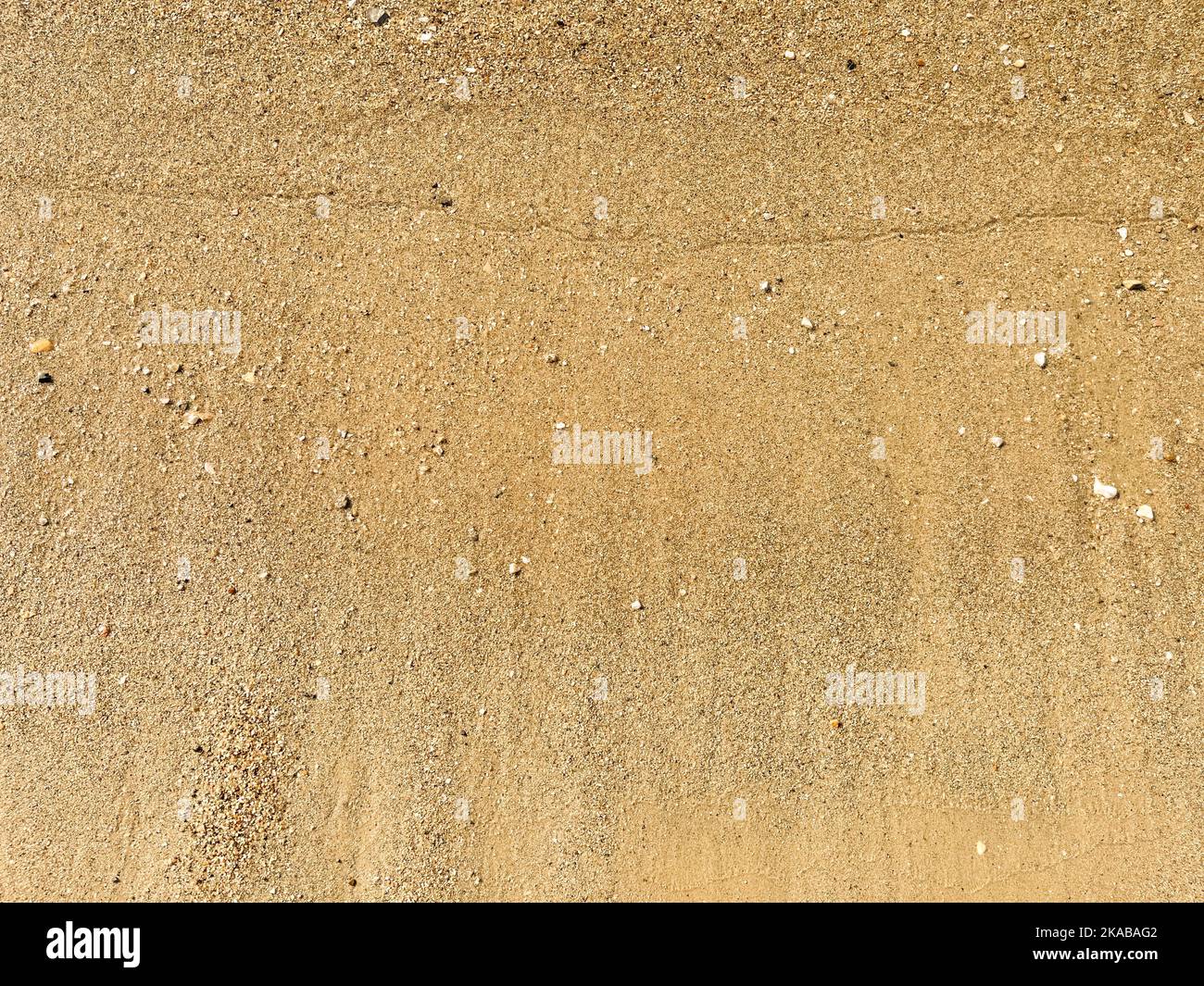A background of sand, small pebbles and flowing wave on the sea beach ...