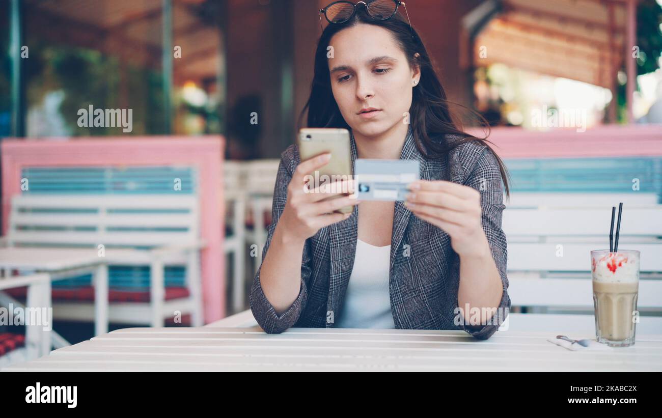 Attractive girl student is paying online with credit card entering ...