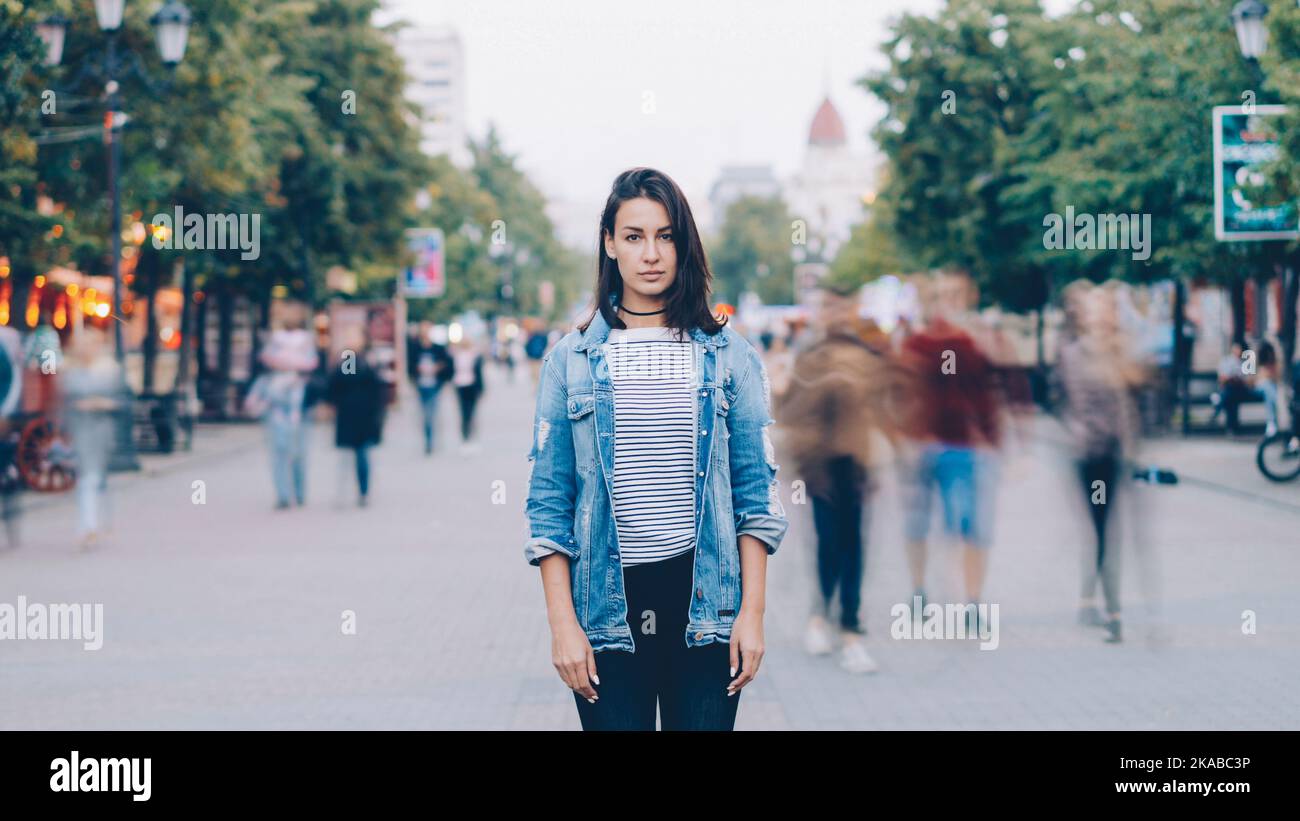 portrait of tired young woman student standing alone in city center and ...