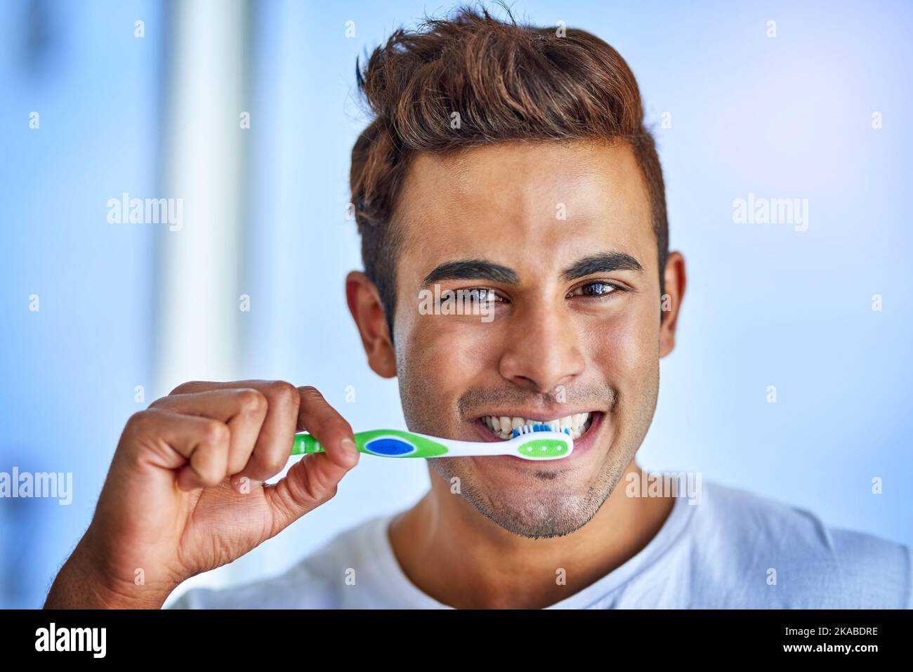 Winners do it twice daily. Portrait of a happy young man brushing his ...