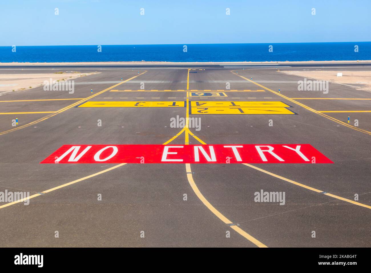 no entry sign at the runway of the airport with ocean in background ...