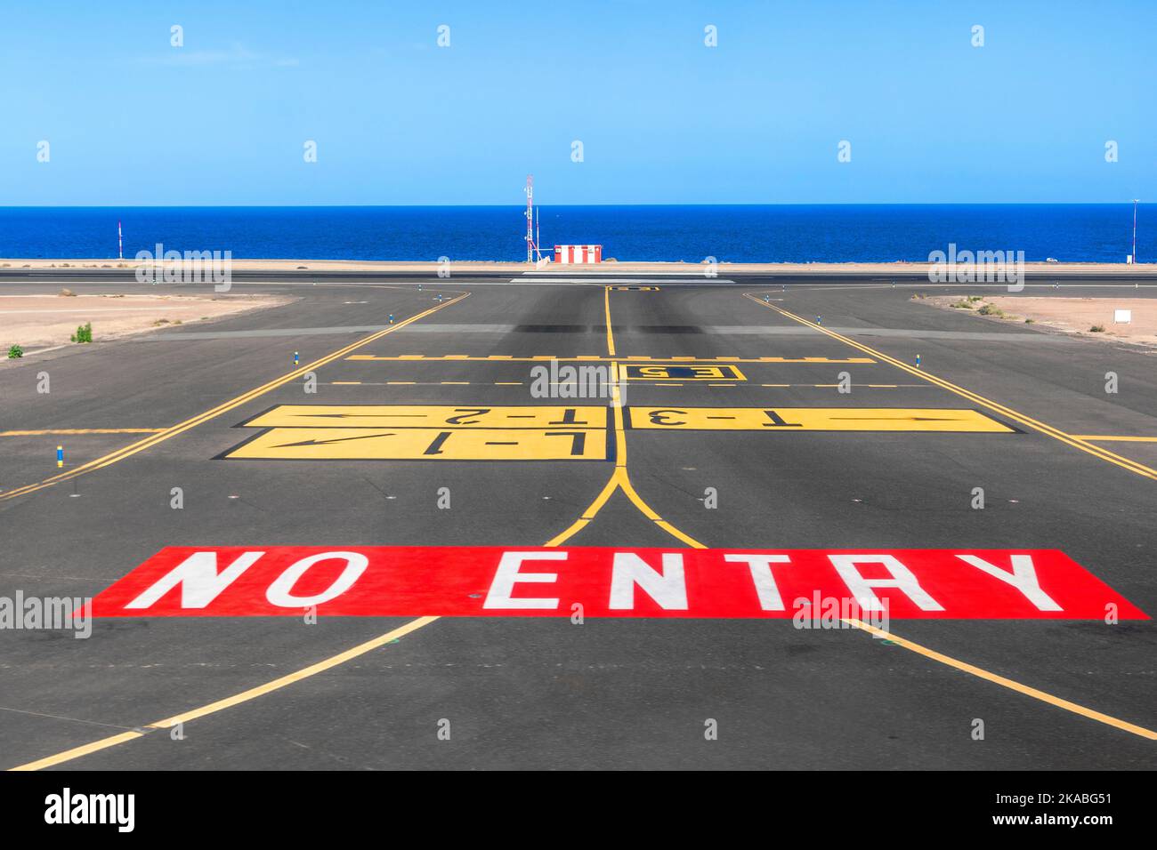 no entry sign at the runway of the airport with ocean in background ...