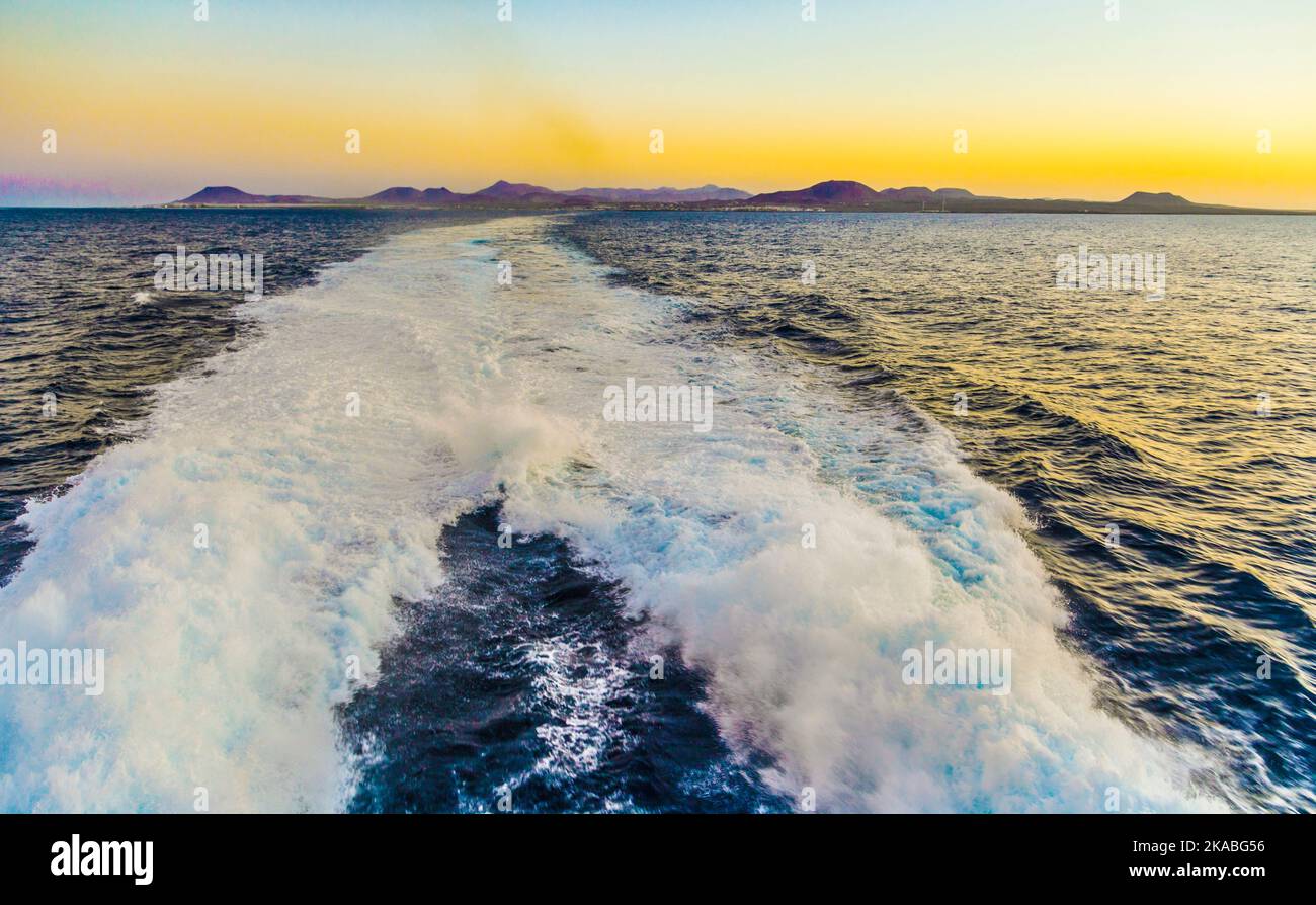 trail of the ship with the island in the background Stock Photo - Alamy