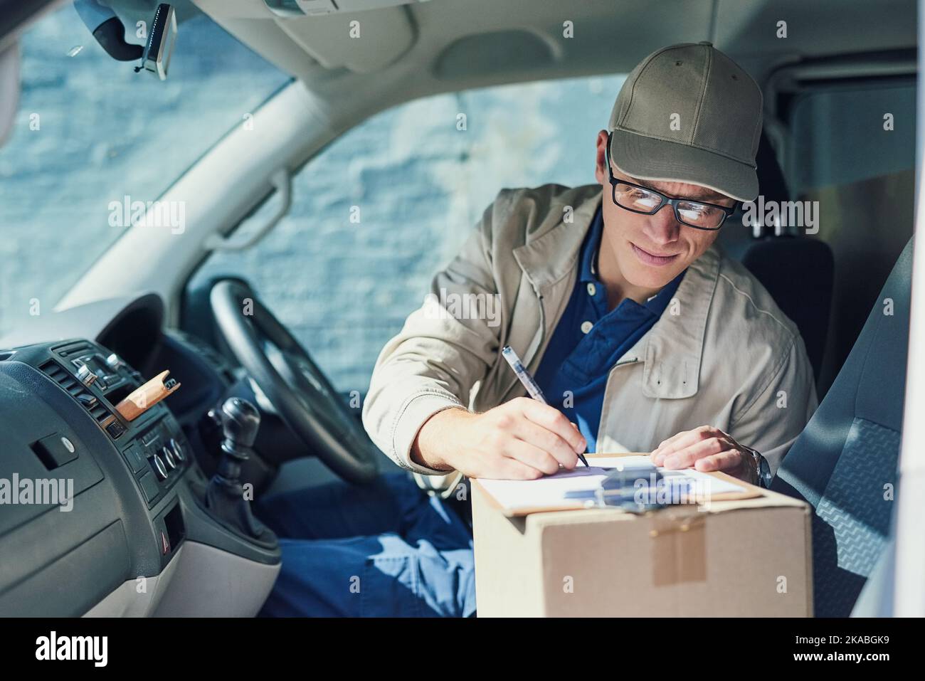 Lets see where to next. a courier writing on a clipboard while sitting ...