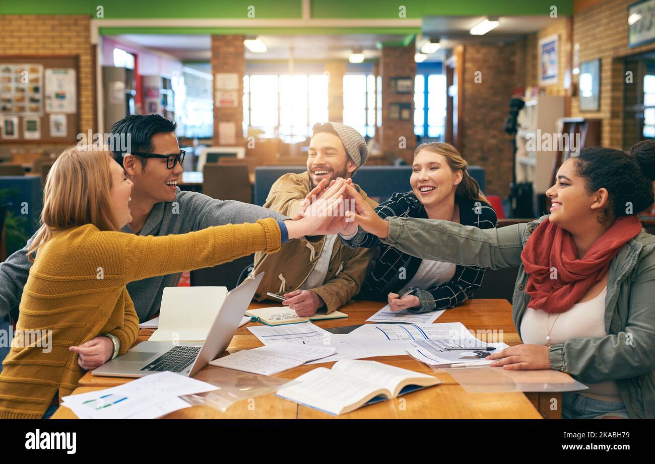 Lets get working. a cheerful young group of students forming a huddle ...