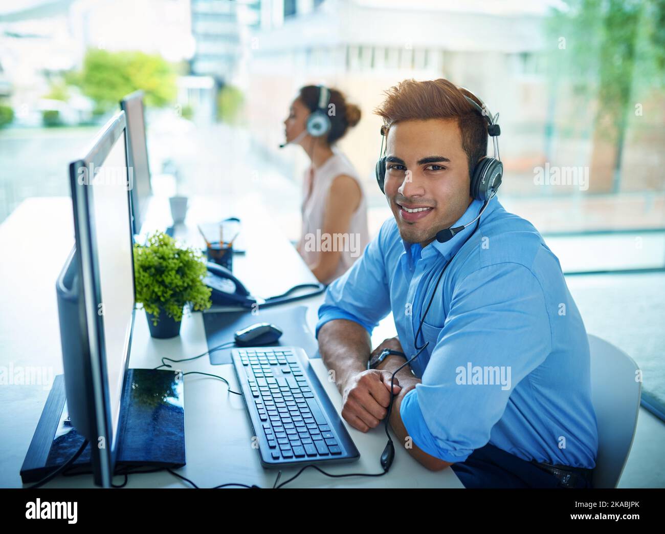 Let us assist you. a young man working in a team of call center agents ...