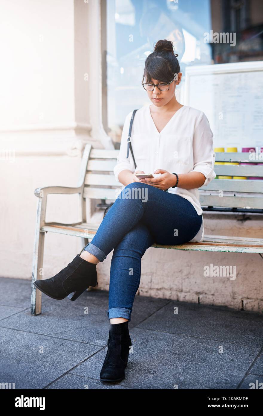The buss should arrive soon. a beautiful young woman texting on her ...