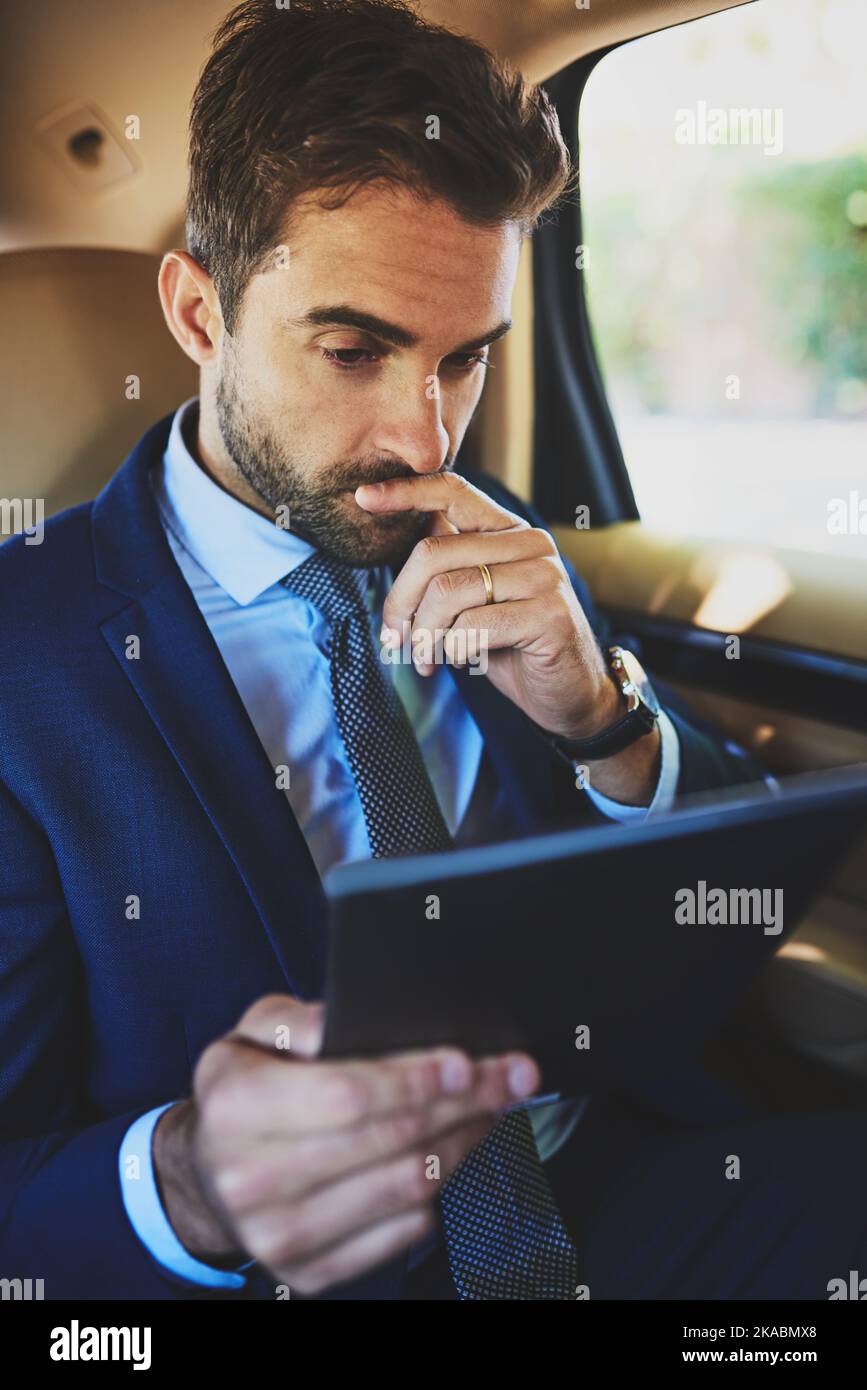 Even when hes in a car he works. a focused young businessman working on ...