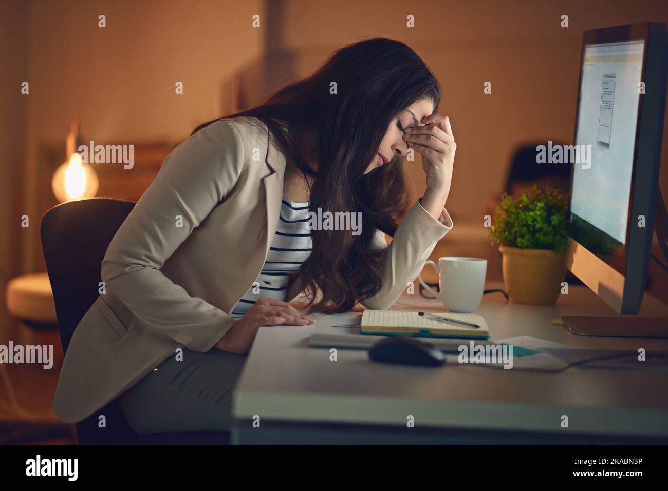 Stress can be a killer. a young businesswoman experiencing strain during a late night at work ...