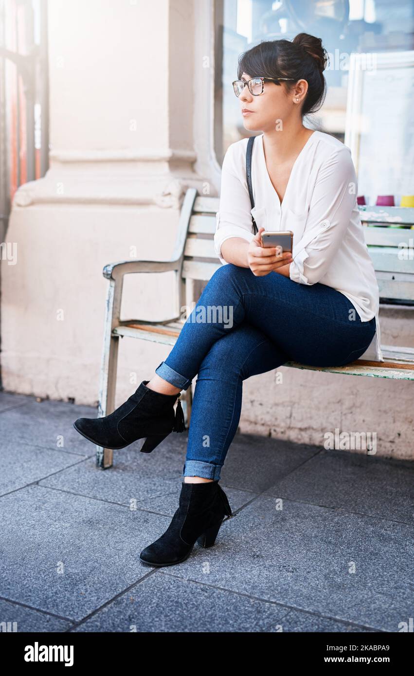 Here comes my ride. a beautiful young woman seated on a bench while ...