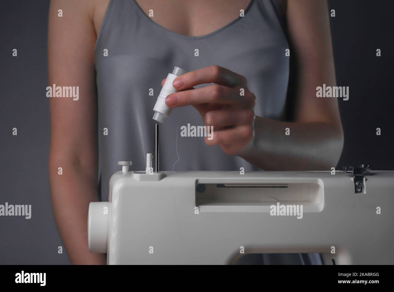 Female hands putting thread spool on sewing machine Stock Photo - Alamy