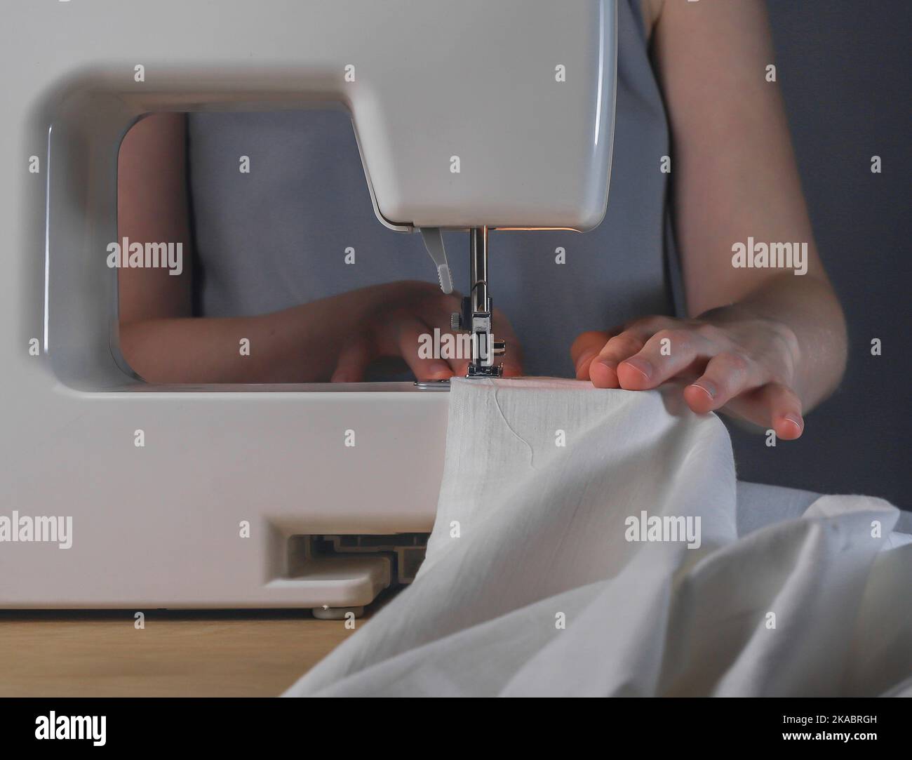 Seamstress hands with linen cloth at sewing machine, working process ...