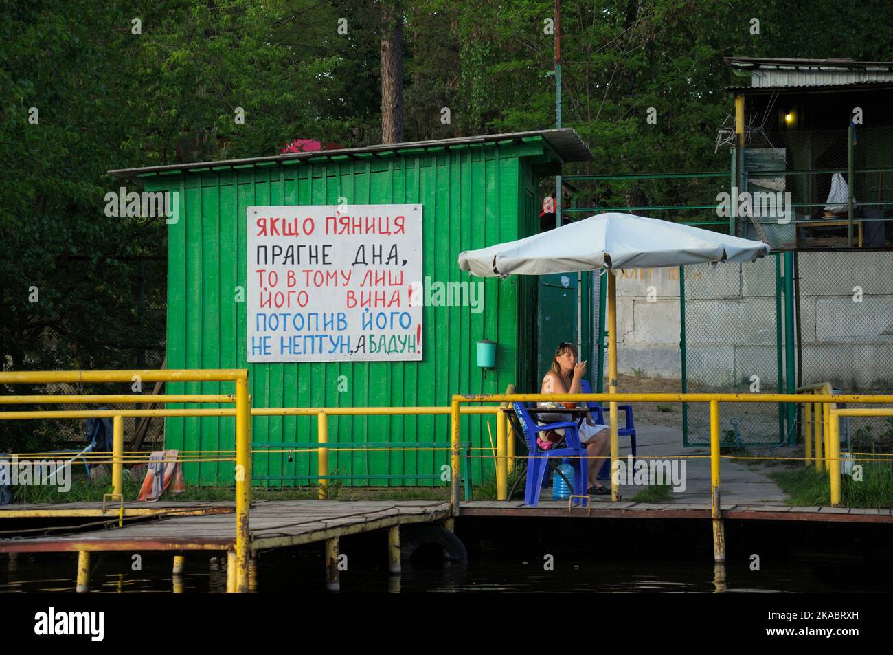 Boat station on the pond, wooden berth, woman manager smoking under ...