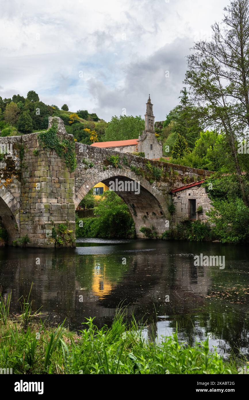Medieval Roman bridge reflected on the water of the river Arnoia in the ...