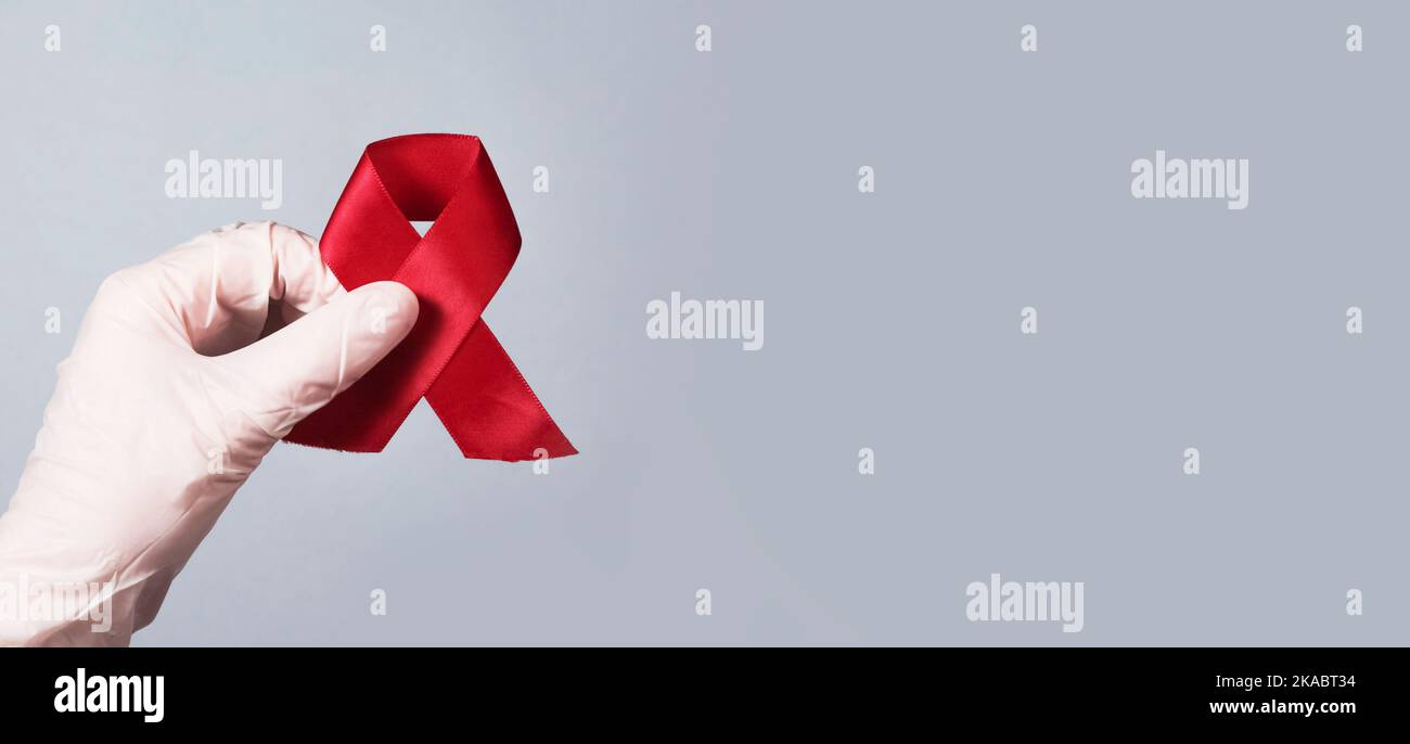 Red ribbon bow for AIDS and HIV awareness day in doctors hands. Medical ...