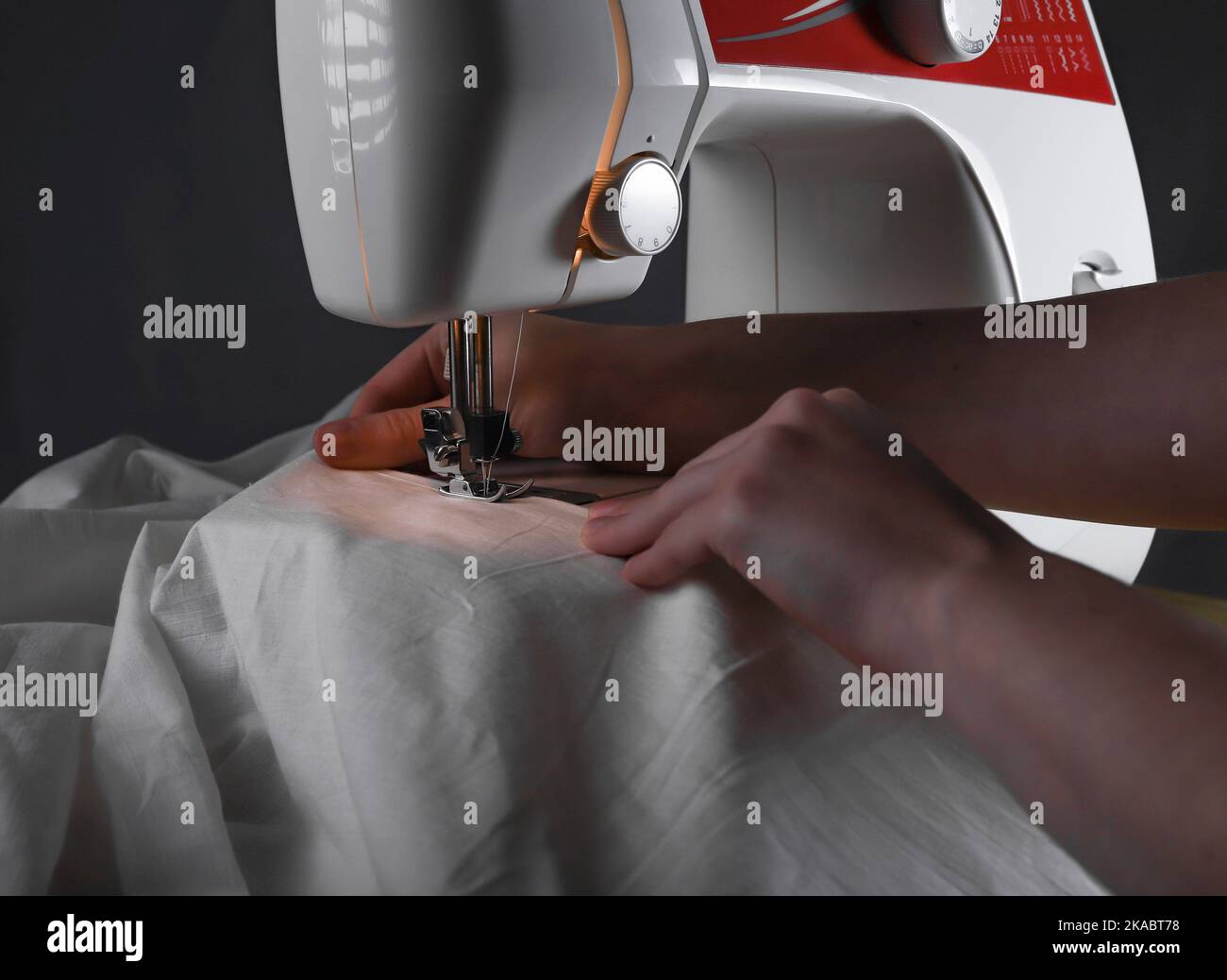 Seamstress hand at sewing machine during working process with cotton ...