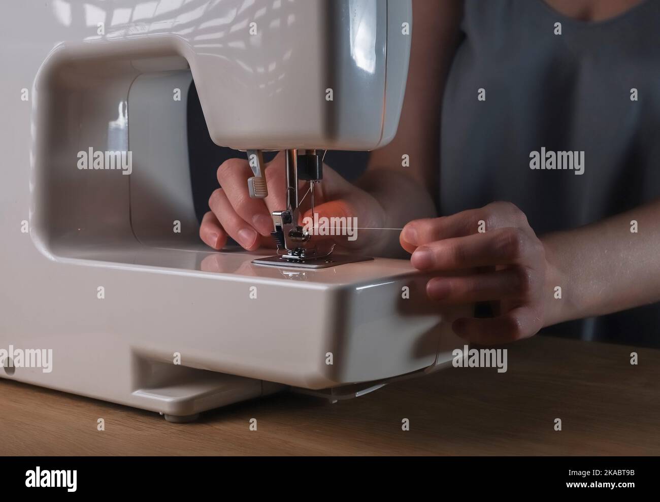 Hands inserting thread through needle hole in sewing machine, details ...