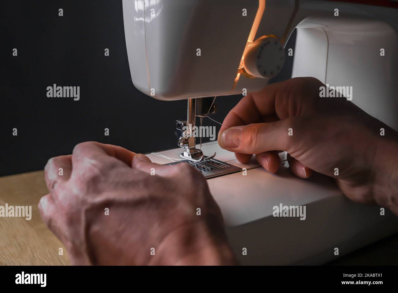 Male hand inserting thread into needle of sewing machine Stock Photo ...