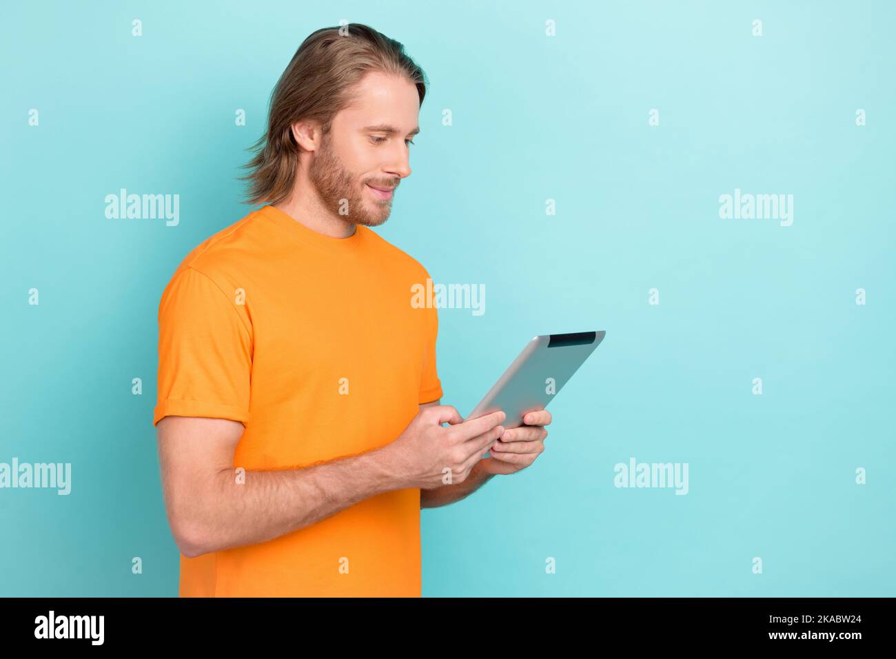 Photo of positive cute guy dressed orange t-shirt chatting apple modern ...