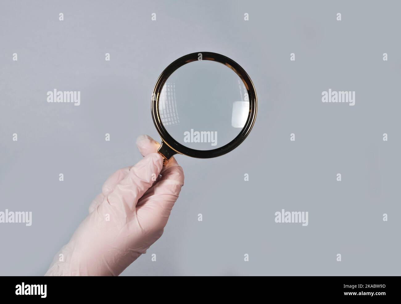 Hand in glove hold magnifying lens, finding and examining diseases with ...