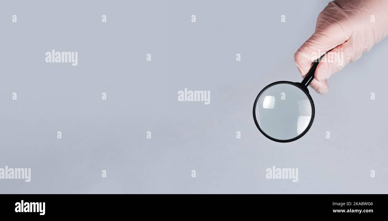 Medical hand in glove with magnifying lens, finding and examining ...
