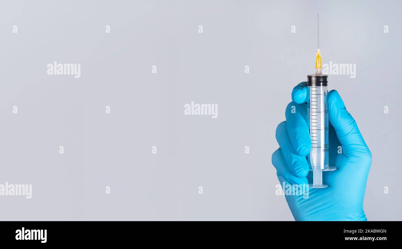 Syringe with needle in doctors hands in glove. Medical banner with copy ...