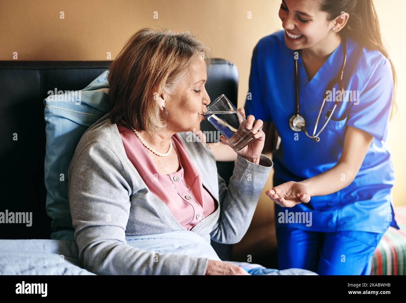 Down the hatch. a nurse giving medication and a glass of water to a ...