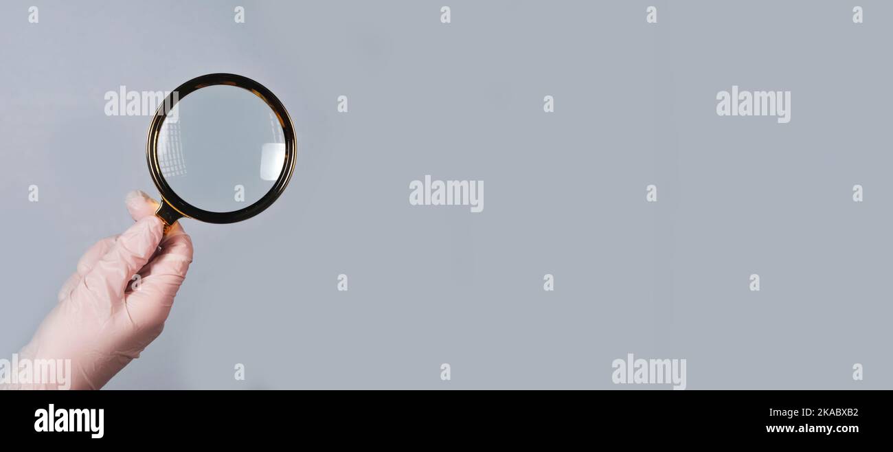 Medical hand in glove with magnifying lens, finding and examining ...