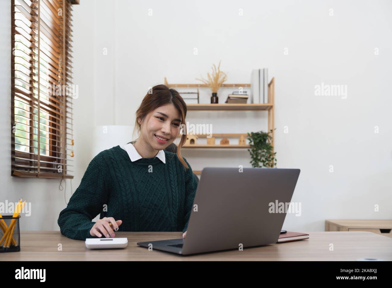 Asian woman accountant using calculator and laptop computer in office ...