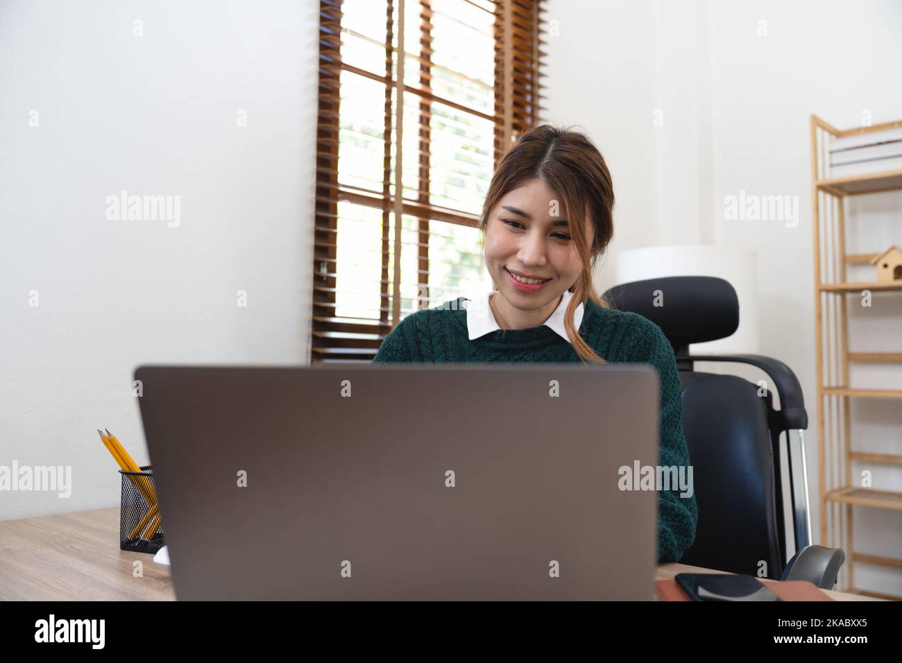 Young smart businesswoman working at home office using laptop having online video meeting with ...