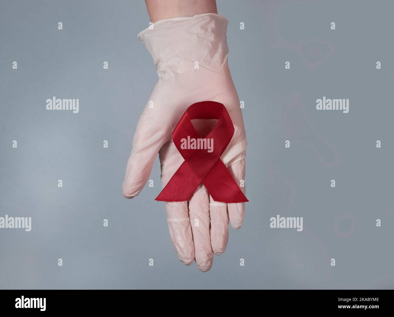 Red ribbon bow as symbol of AIDS and HIV awareness day, in doctor hand ...