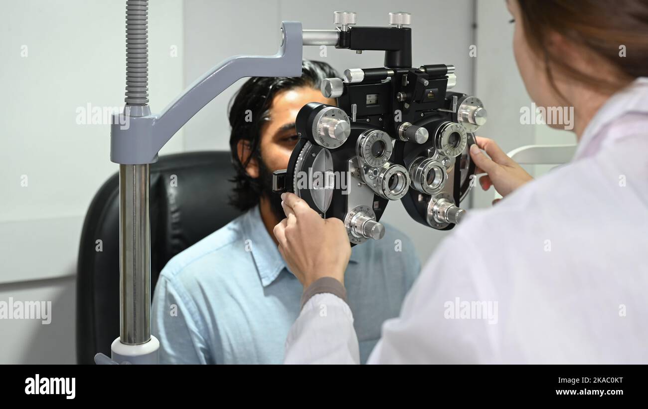Young Indian male patient checking eye vision with phoropter eyesight ...