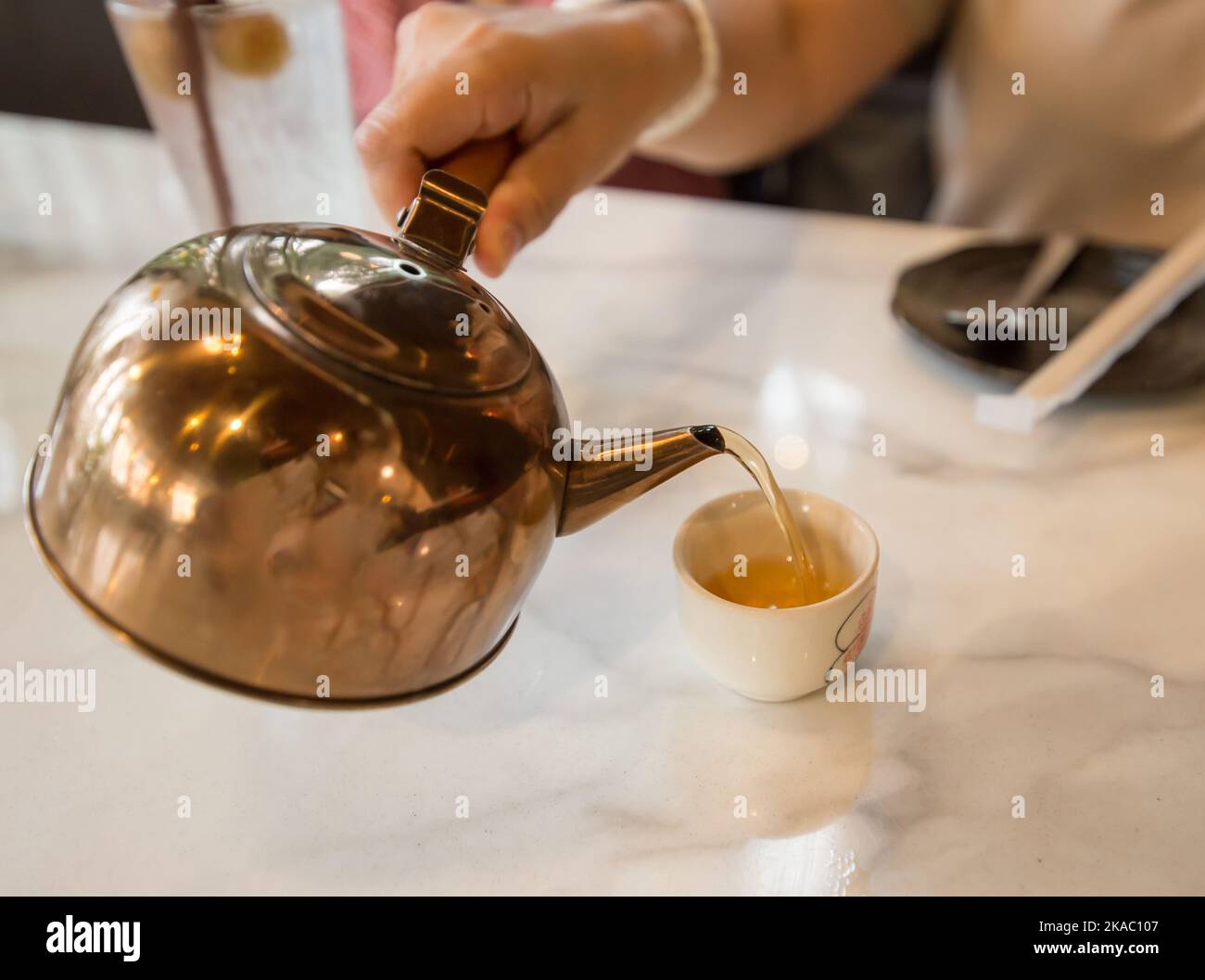 Pouring tea with a brass teapot in to the small cup Stock Photo - Alamy