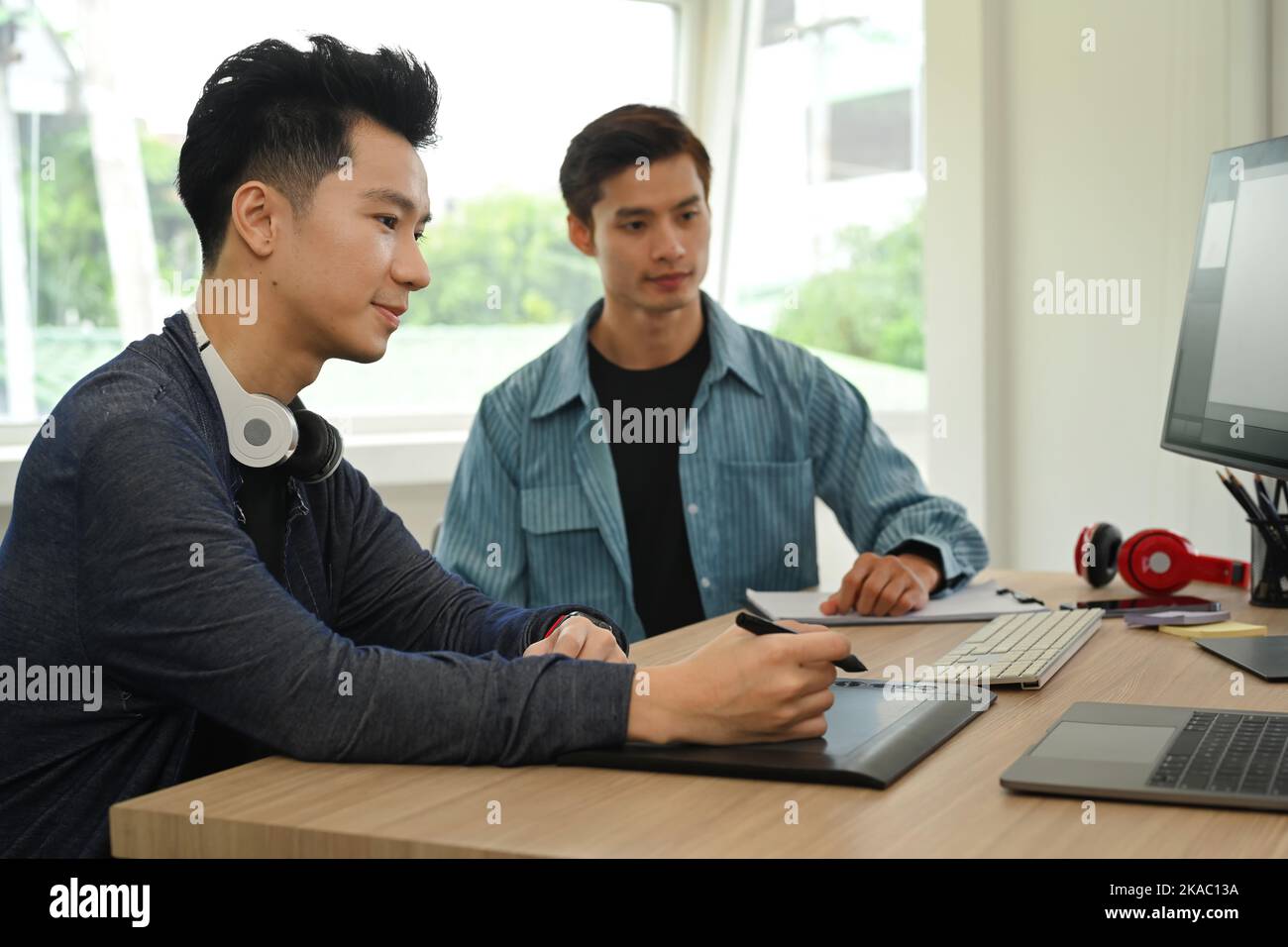 Two young content creator working together, editing video footage with ...