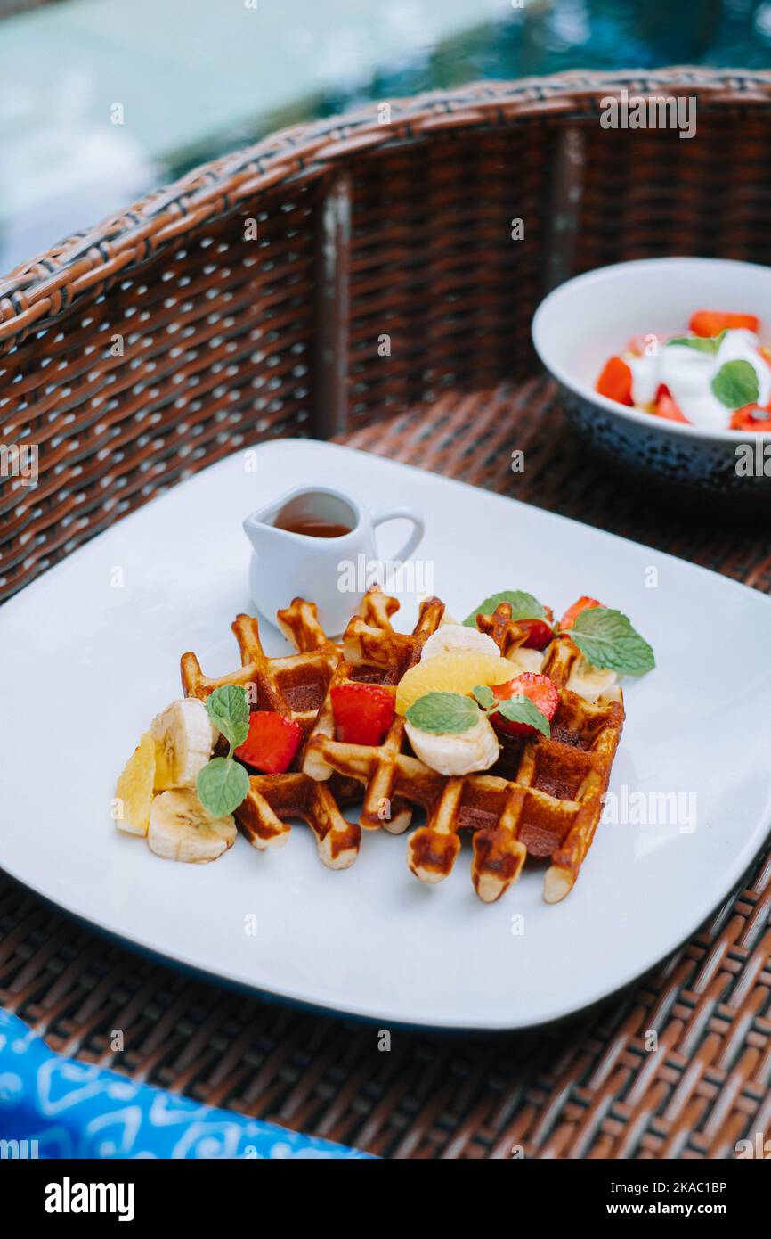 2 pieces of Waffles in a plate with indonesian fruit salad and a cup of ...