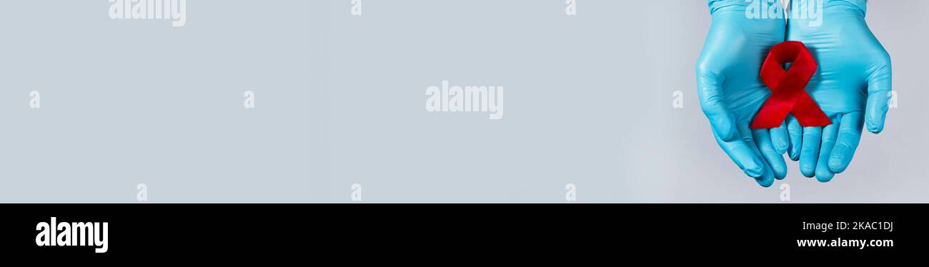 Red ribbon bow for AIDS and HIV awareness in hands. Medical banner with ...