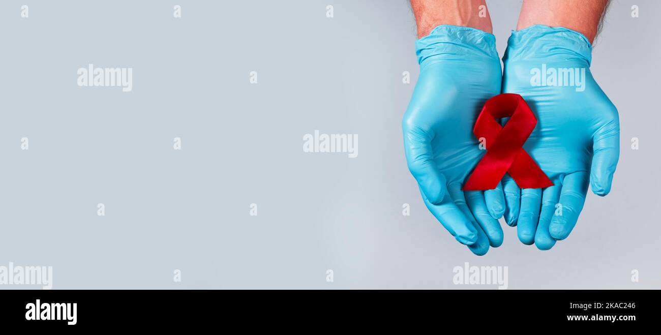 Red ribbon bow for AIDS and HIV awareness in hands. Medical banner with ...