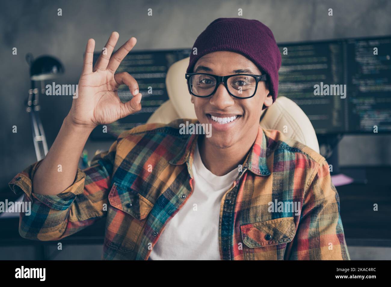 Portrait of cheerful positive hacker guy sit chair hand fingers demonstrate okey symbol ...