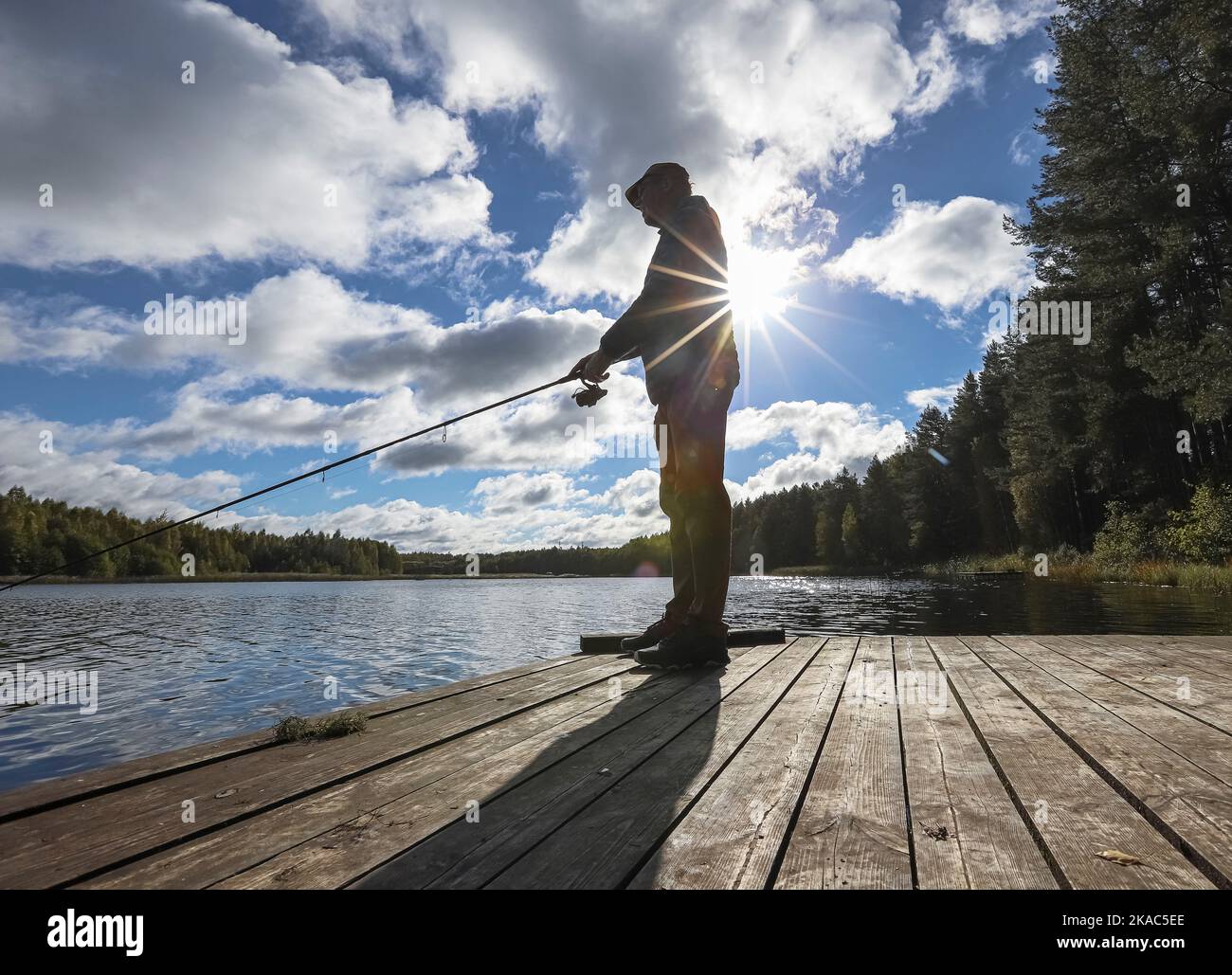Fisherman fishing alone with rod and sun Stock Photo - Alamy