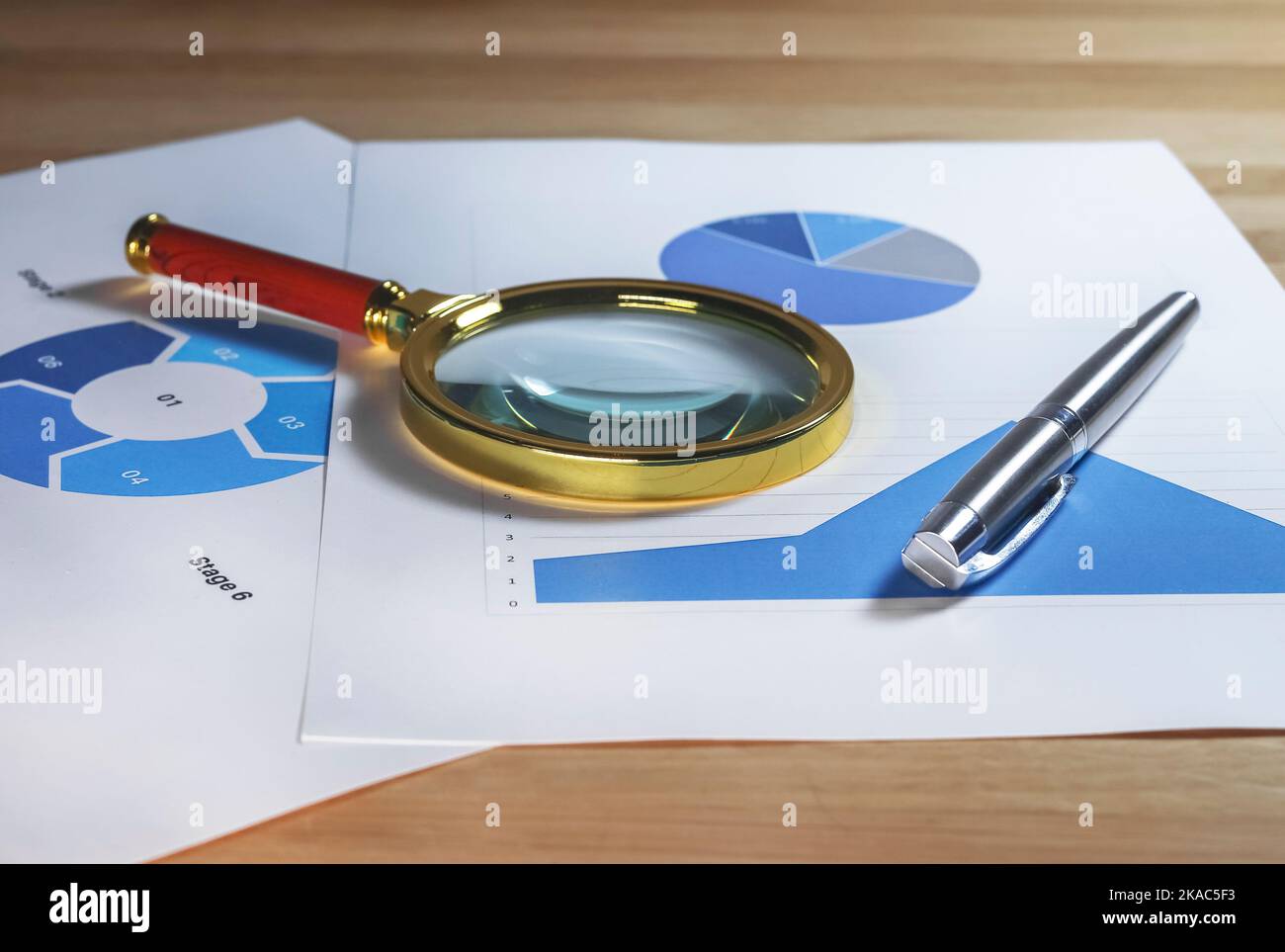 Magnifying lens on documents with business charts and graphs Stock ...