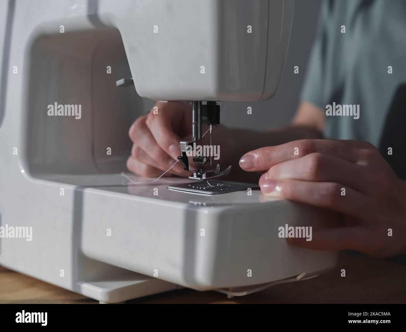 Hands inserting thread through needle hole in sewing machine Stock ...