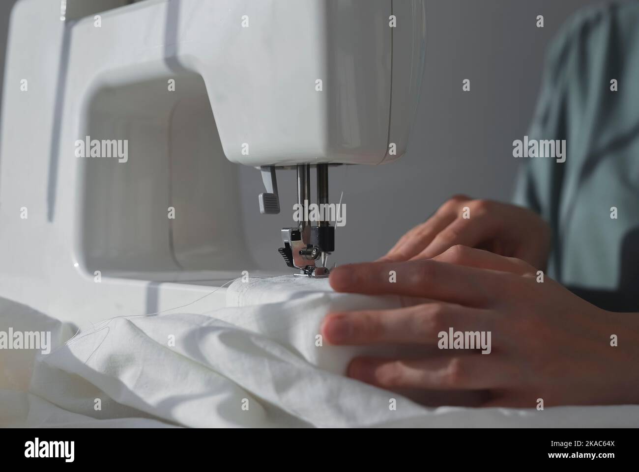 Seamstress hands with linen cloth at sewing machine, working process ...