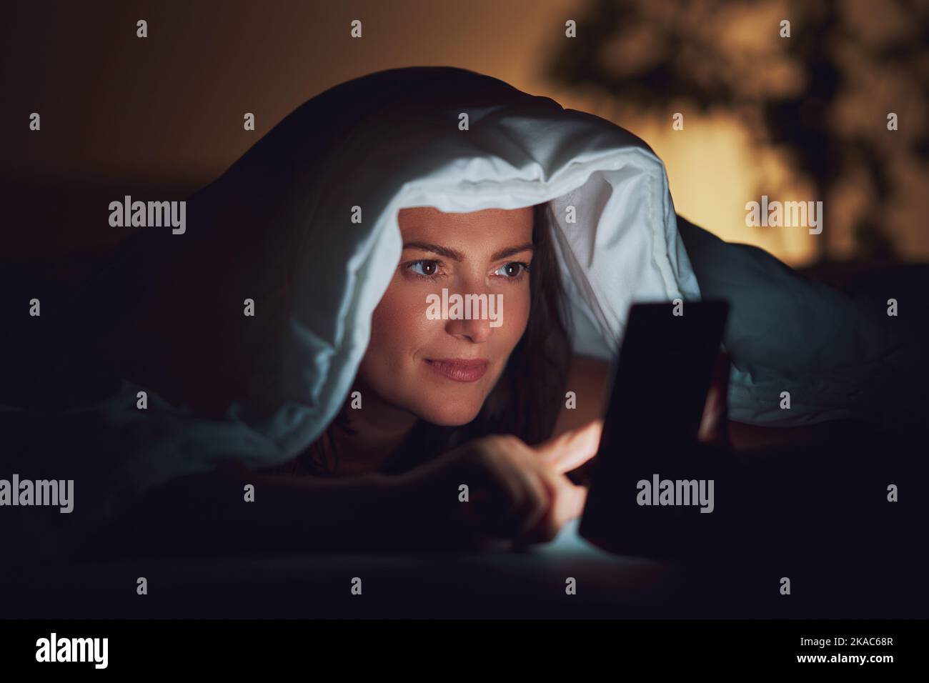 Woman at night in bed with phone Stock Photo - Alamy