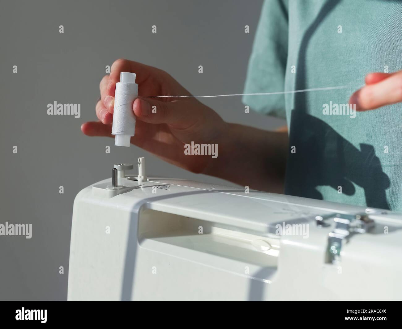 Hands putting thread spool on sewing machine Stock Photo - Alamy